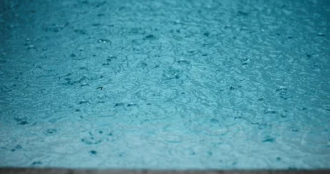 Raindrops splashing blue puddle water of... | Stock Video | Pond5