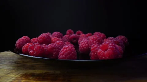 Raspberries on a plate and black backgro... | Stock Video | Pond5