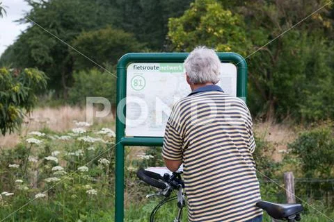 Reading the route map by biker Elderly Biker is reading the route map ...