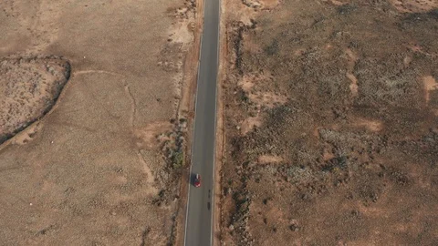 Red car driving on a desert road aerial | Stock Video | Pond5