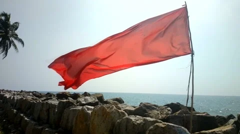 red flag flying over sea coast near vill... | Stock Video | Pond5