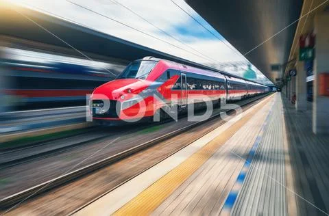 Photograph: Red high speed train in motion on the railway station ...