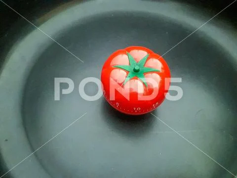 Photograph: Red pomodoro timer in tomato shape on a black texture ...
