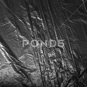 Reflected light and shadow on creases and folds in black plastic ...