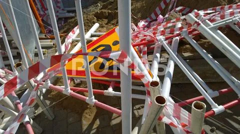 Road works sign denoting construction work and damaged metal fencing ...