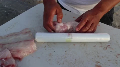 Rolling up a fish filet in saran wrap on... | Stock Video | Pond5
