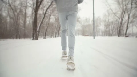 Running athlete in winter park, rear vie... | Stock Video | Pond5