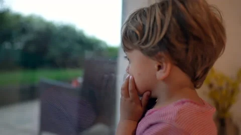 Sad child leaning on window staring out | Stock Video | Pond5