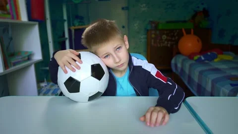 Sad child sits with a soccer ball at the... | Stock Video | Pond5