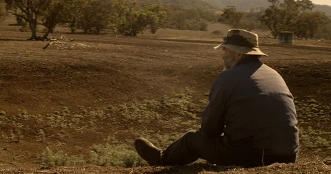 Sad farmer sitting on empty dam wall on ... | Stock Video | Pond5