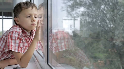 sad little boy standing near a window at... | Stock Video | Pond5