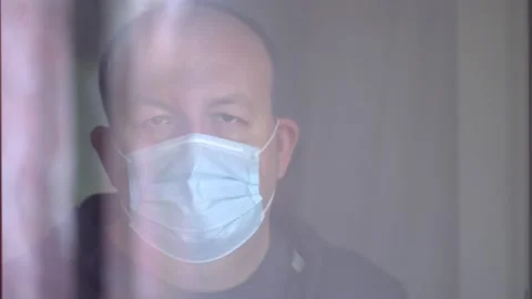 Sad Man In Face Mask Looking Through Win... | Stock Video | Pond5