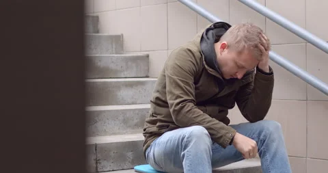 A sad man sits on the steps. The emotion... | Stock Video | Pond5