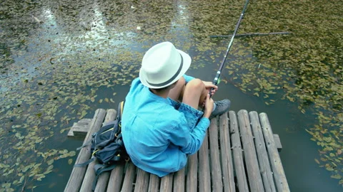 sad teen boy with a fishing rod sits on ... | Stock Video | Pond5