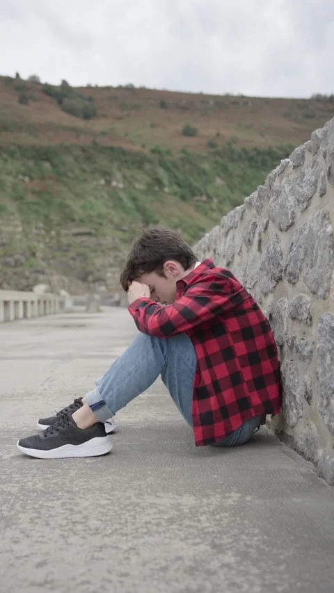 Sad teenager boy sitting on ground. Depr... | Stock Video | Pond5
