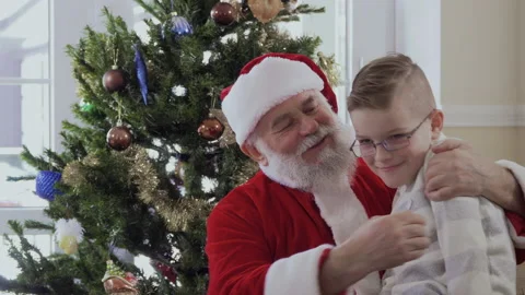 Santa hugs and squeezes the boy near fir... | Stock Video | Pond5
