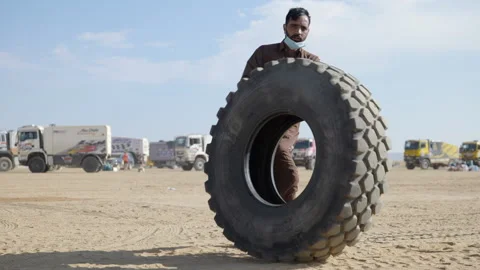 Saudi Arabian man pushing a huge tyre ac... | Stock Video | Pond5