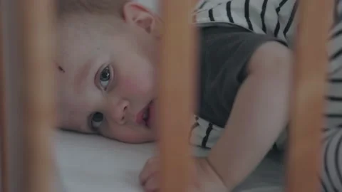 scared baby lying in wooden crib falling... | Stock Video | Pond5