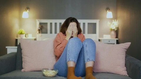Scared young woman sitting on the sofa, ... | Stock Video | Pond5