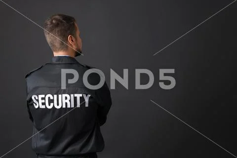 Security guard in uniform on black background, back view. Space for ...