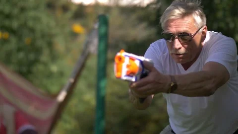 Senior man in a toy gun fight on nature | Stock Video | Pond5