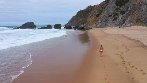 Sexy woman in a bikini walks over a sand... | Stock Video | Pond5