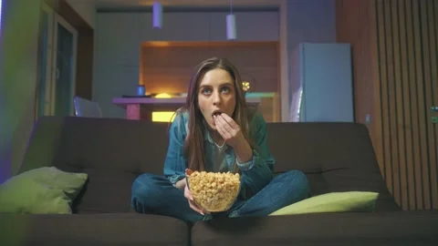 A shocked young girl with popcorn is wat... | Stock Video | Pond5