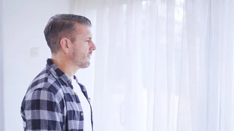 Side view of man looking out the home wi... | Stock Video | Pond5