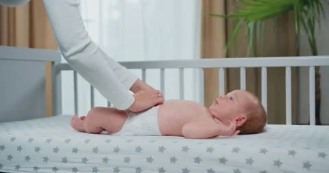 Side view. Mother puts on clean diaper d... | Stock Video | Pond5