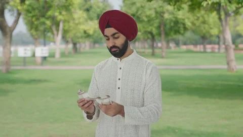 Sikh Indian man counting money in park | Stock Video | Pond5