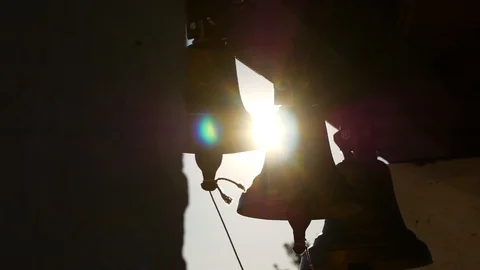 Silhouette of bells at sunset. Sun rays | Stock Video | Pond5