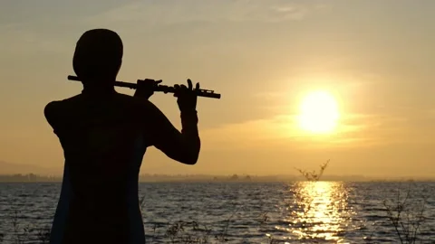 silhouette of man playing flute with wat... | Stock Video | Pond5