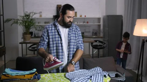 Single handsome father ironing clothes a... | Stock Video | Pond5