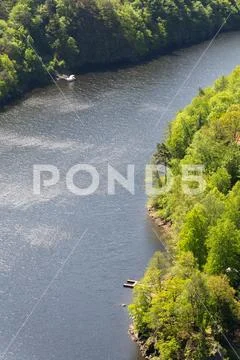 Single ship and lonely pier on river, breathtaking green woods nature ...