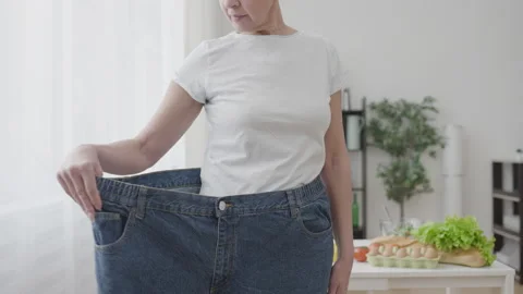Slim lady wearing extra large jeans, sat... | Stock Video | Pond5