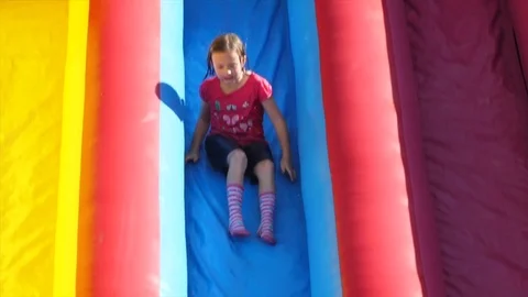 Slow motion cute girl slides down bouncy... | Stock Video | Pond5