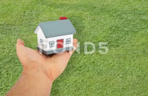 Small house in hand on green background ~ Hi Res #20439103