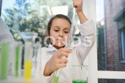 Smart primary school student using pipette, drips reagent into a test ...