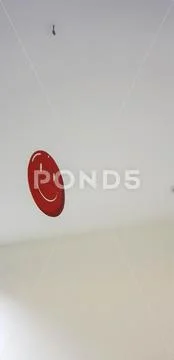 A smiley emoticon hanging from the ceiling. The smileys are red and ...