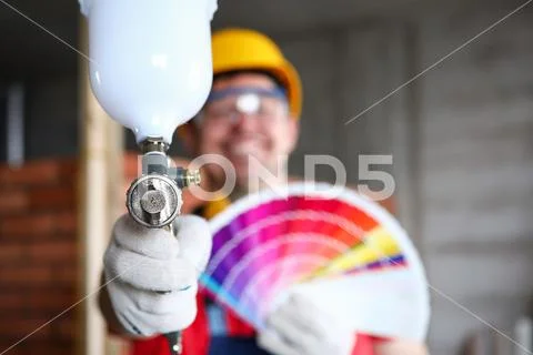 Smiling builder shows spray gun and color swatches ~ Hi Res #138383988