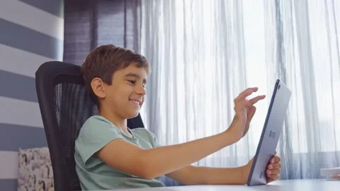 Smiling kid holding and tapping on a tab... | Stock Video | Pond5