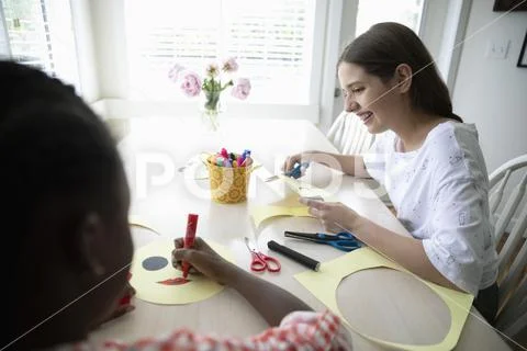 Smiling tween girl friends coloring, doing art project at table ...