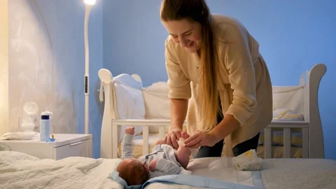 Smiling young mother changing diapers an... | Stock Video | Pond5