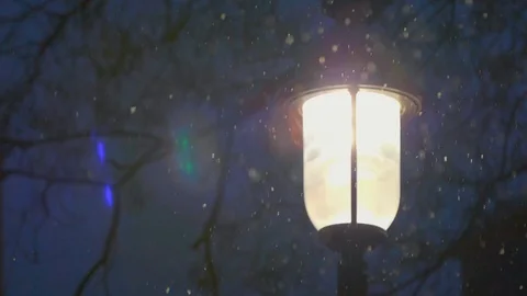 Snow falling around bright light lamp po... | Stock Video | Pond5