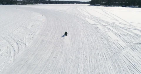 Snowmobile riding on snowy frozen lake i... | Stock Video | Pond5
