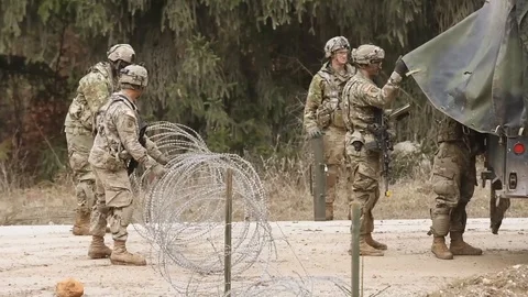 Soldiers stretch barb wire along a dirt ... | Stock Video | Pond5