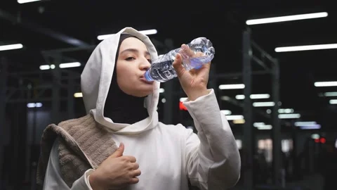 A sporty Muslim woman is drinking water ... | Stock Video | Pond5