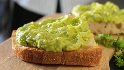 Spreading mashed avocado on toasted sour... | Stock Video | Pond5