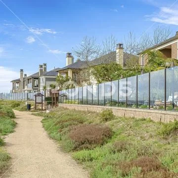 Square Pathway along homes with glass fences under skyscape of blue sky ...