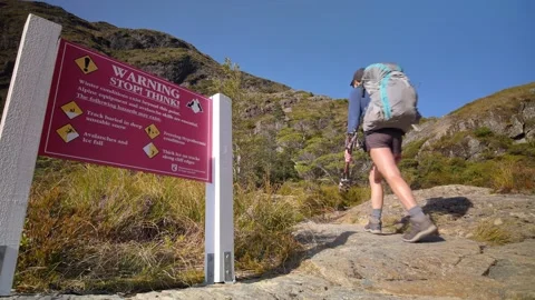 Static, hikers walk past alpine warning ... | Stock Video | Pond5
